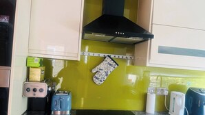 Cozinha com exaustor preto, torradeira, cafeteira e chaleira na bancada.