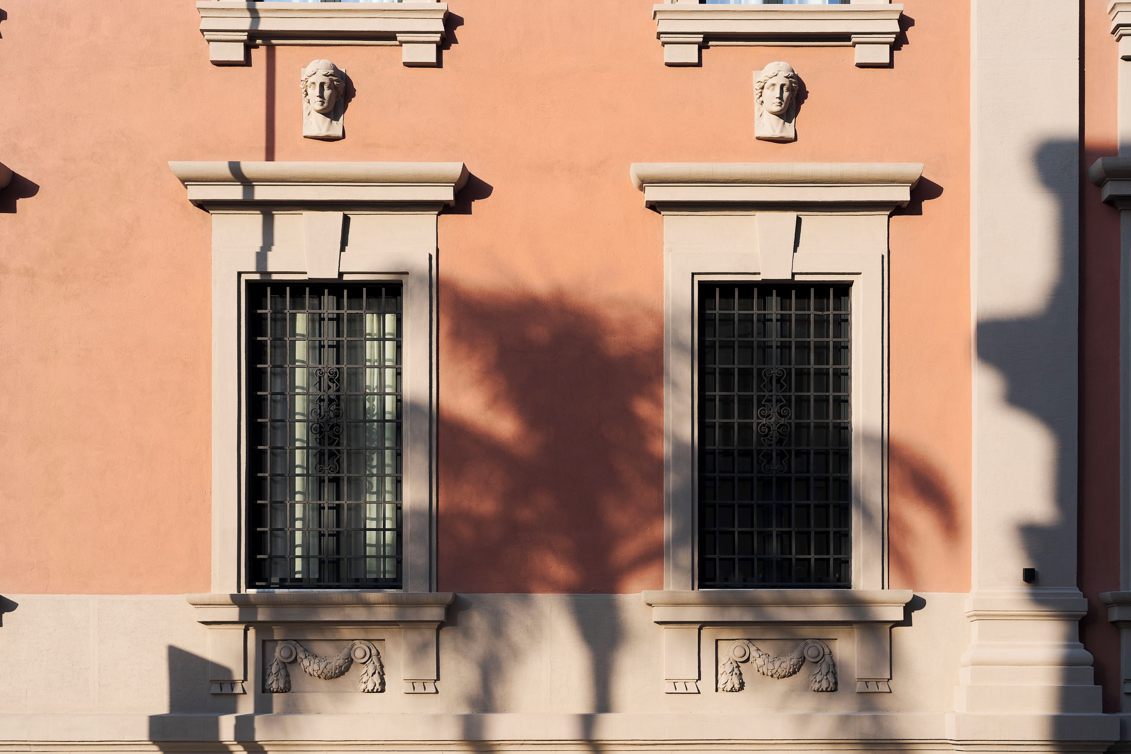 Fachada de edifício com duas janelas, molduras decorativas e um pilar central.