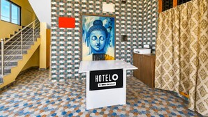 Uma área de recepção de hotel com um quadro de Buda, uma escadaria e um piso estampado.