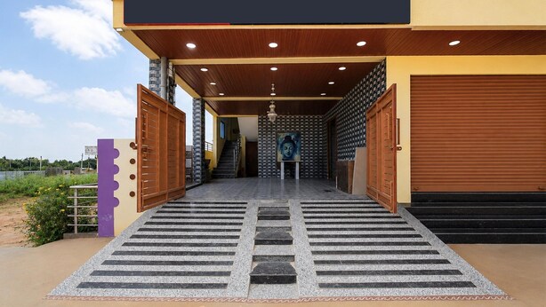 Entrada de um edifício moderno com galeria coberta, degraus até uma porta e vista do céu.