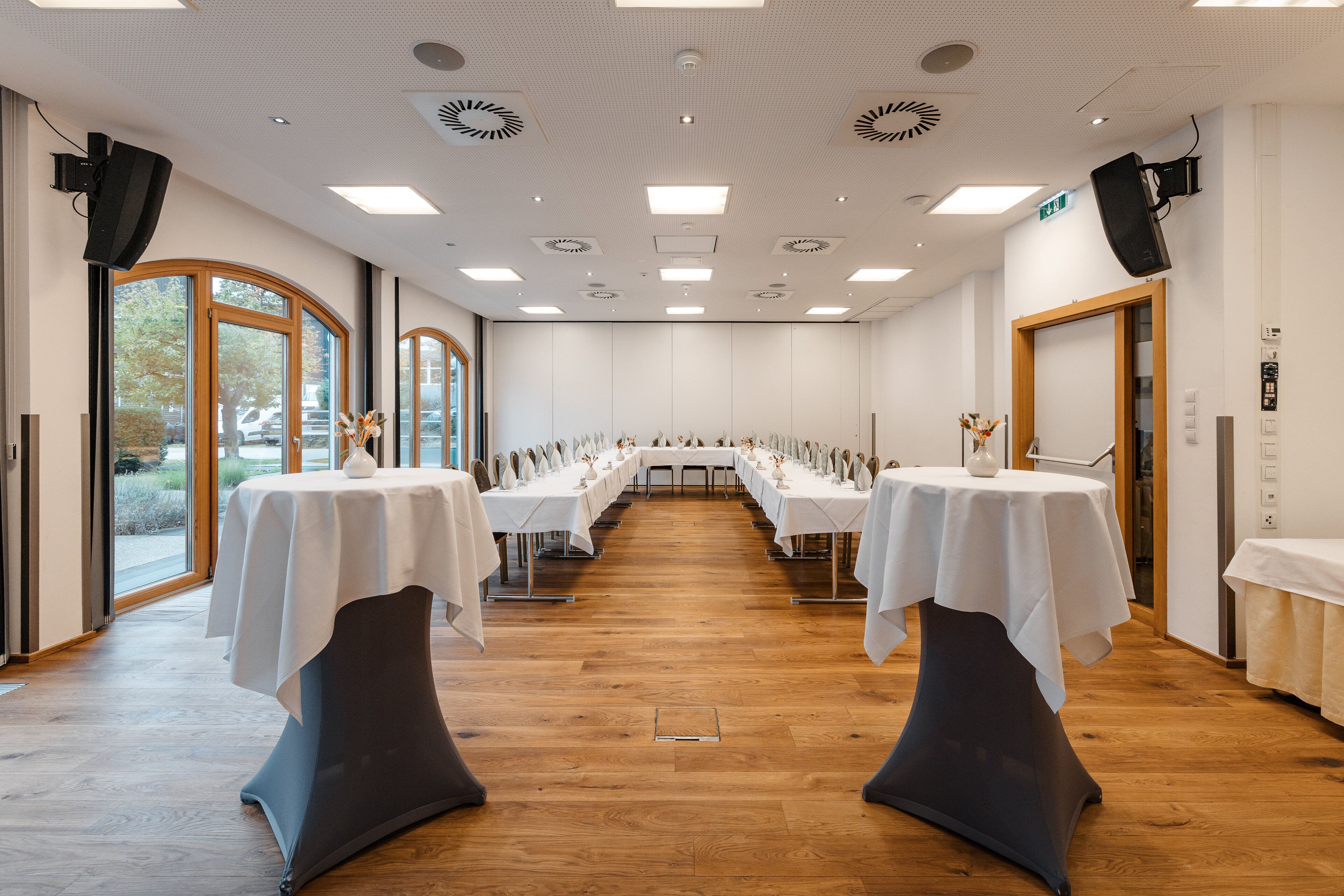Uma sala de conferências com mesas compridas, cadeiras e piso de madeira.