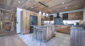Uma cozinha moderna com armários de madeira, uma ilha central com banquetas e iluminação pendente.