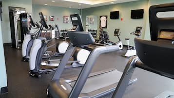 Uma academia com várias esteiras, aparelhos de musculação e halteres.