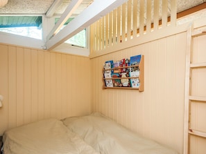 Quarto com uma cama, uma estante de madeira e teto inclinado.