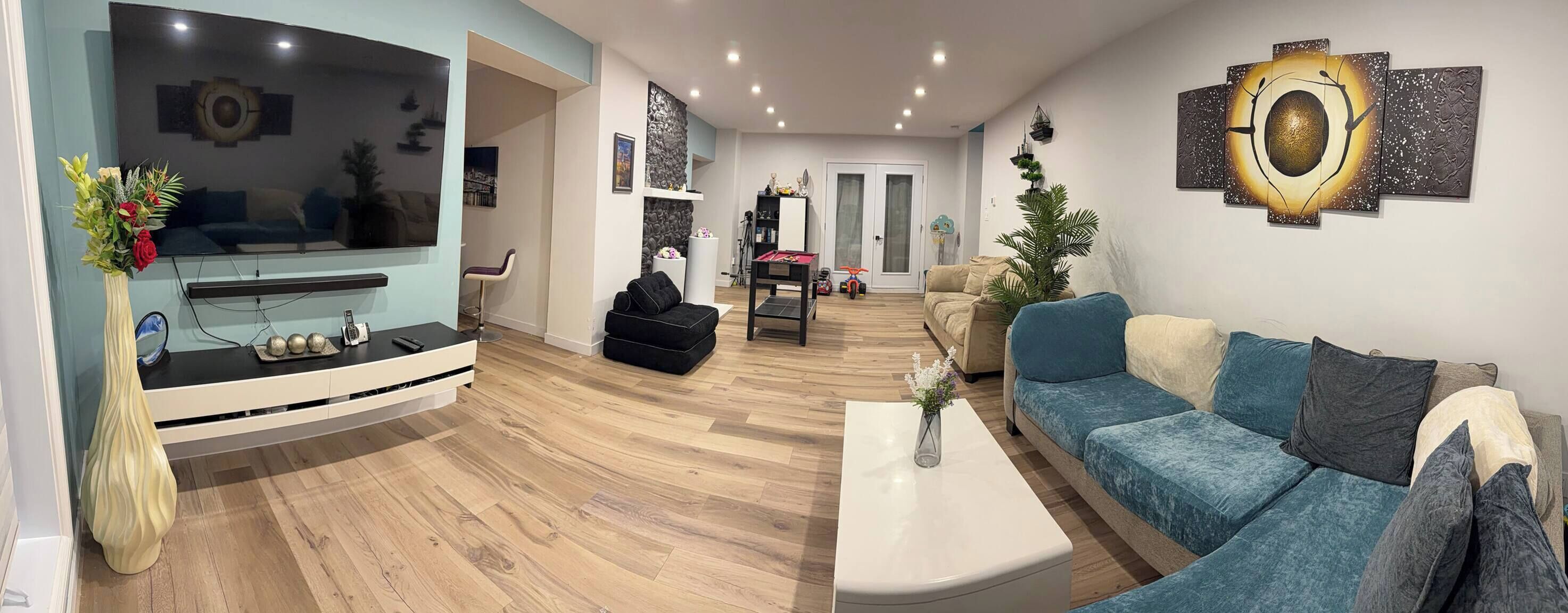 Uma sala de estar moderna com televisão de tela plana, um sofá, uma mesa de centro e plantas decorativas.