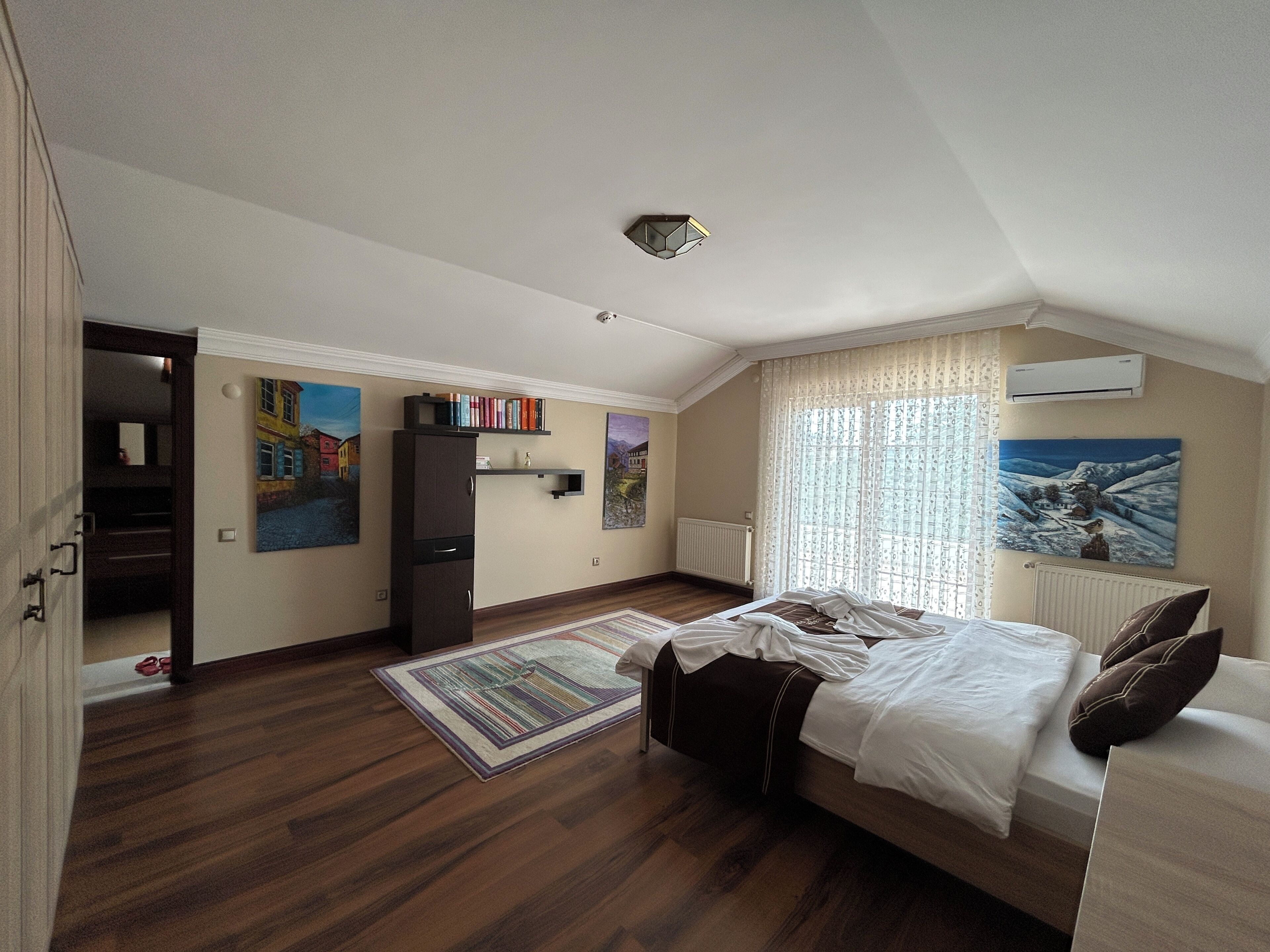 Um quarto com cama, guarda-roupa, radiador e um quadro na parede.