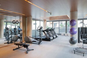 Uma academia com esteiras, aparelhos de musculação e bolas de exercício.