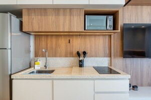 Uma cozinha moderna com micro-ondas embutido, eletrodomésticos de aço inoxidável e uma bancada elegante.