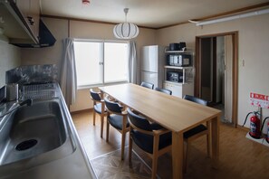 Cozinha compacta com mesa de jantar, cadeiras, geladeira, micro-ondas e extintor de incêndio.