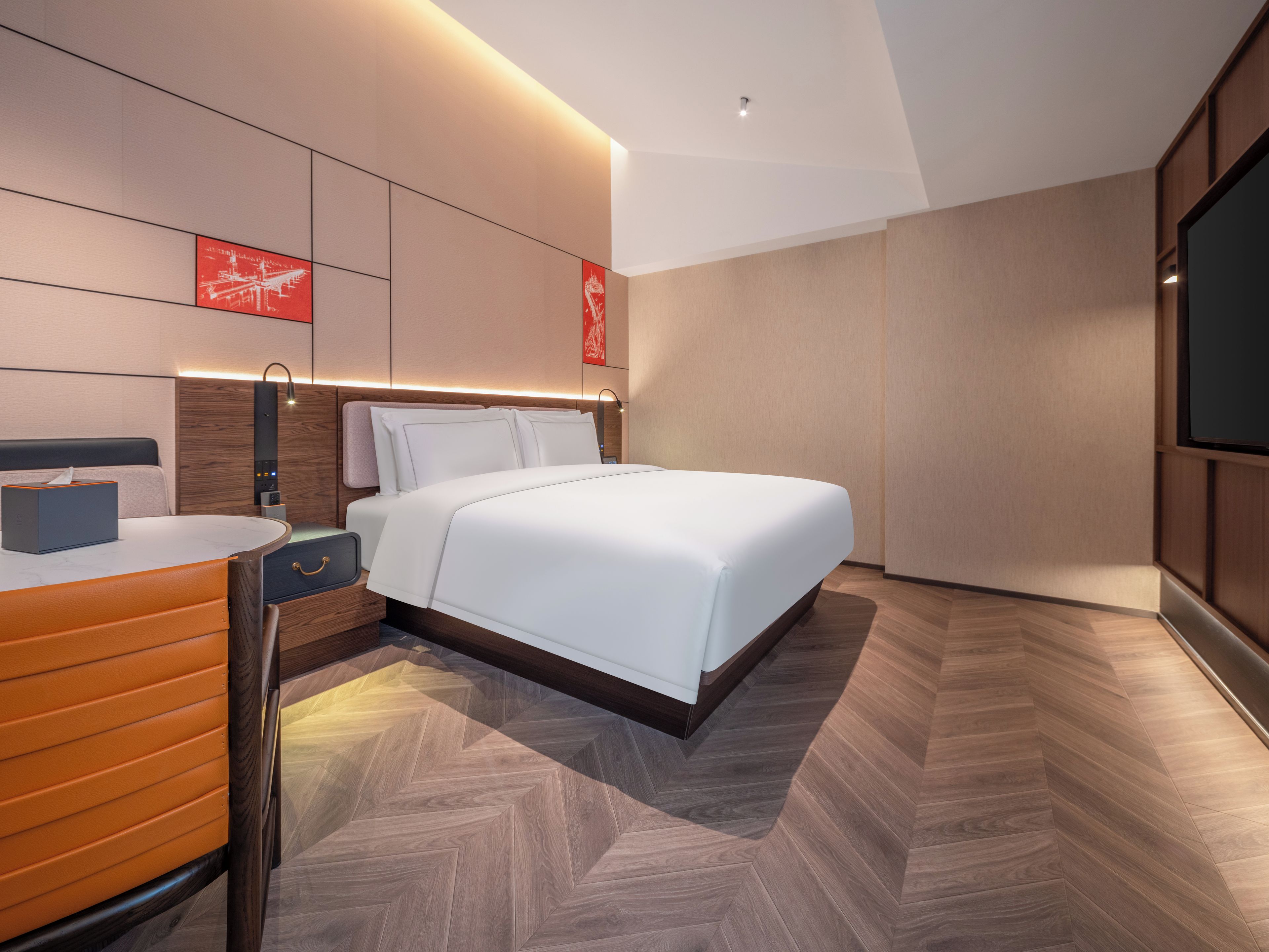 Quarto de hotel moderno com cama, mesa de cabeceira e televisão de tela plana.