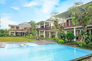 Um hotel com piscina, várias varandas e vegetação exuberante.