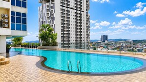 Piscina no terraço com vista para um edifício alto e paisagem urbana.