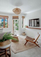 Uma sala de estar moderna com um sofá, uma poltrona, uma mesa redonda e um lustre.