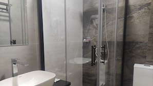Uma casa de banho moderna com lavatório branco, cabine de duche com vidro e sanita.