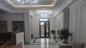 Um corredor com piso de mármore, um sofá, uma televisão e uma porta que dá para o exterior.