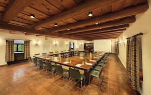 Uma sala de conferências com uma mesa comprida, cadeiras e um projetor.