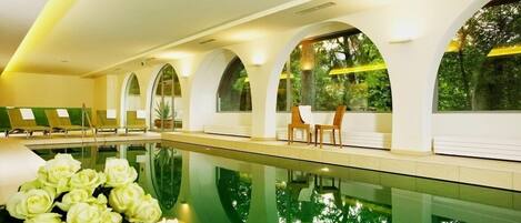 Piscina com cadeiras de descanso e um vaso de flores.