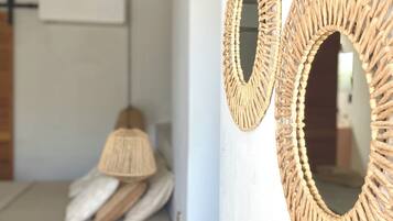 Quarto com cama, luminária pendente e dois espelhos de parede em tear.