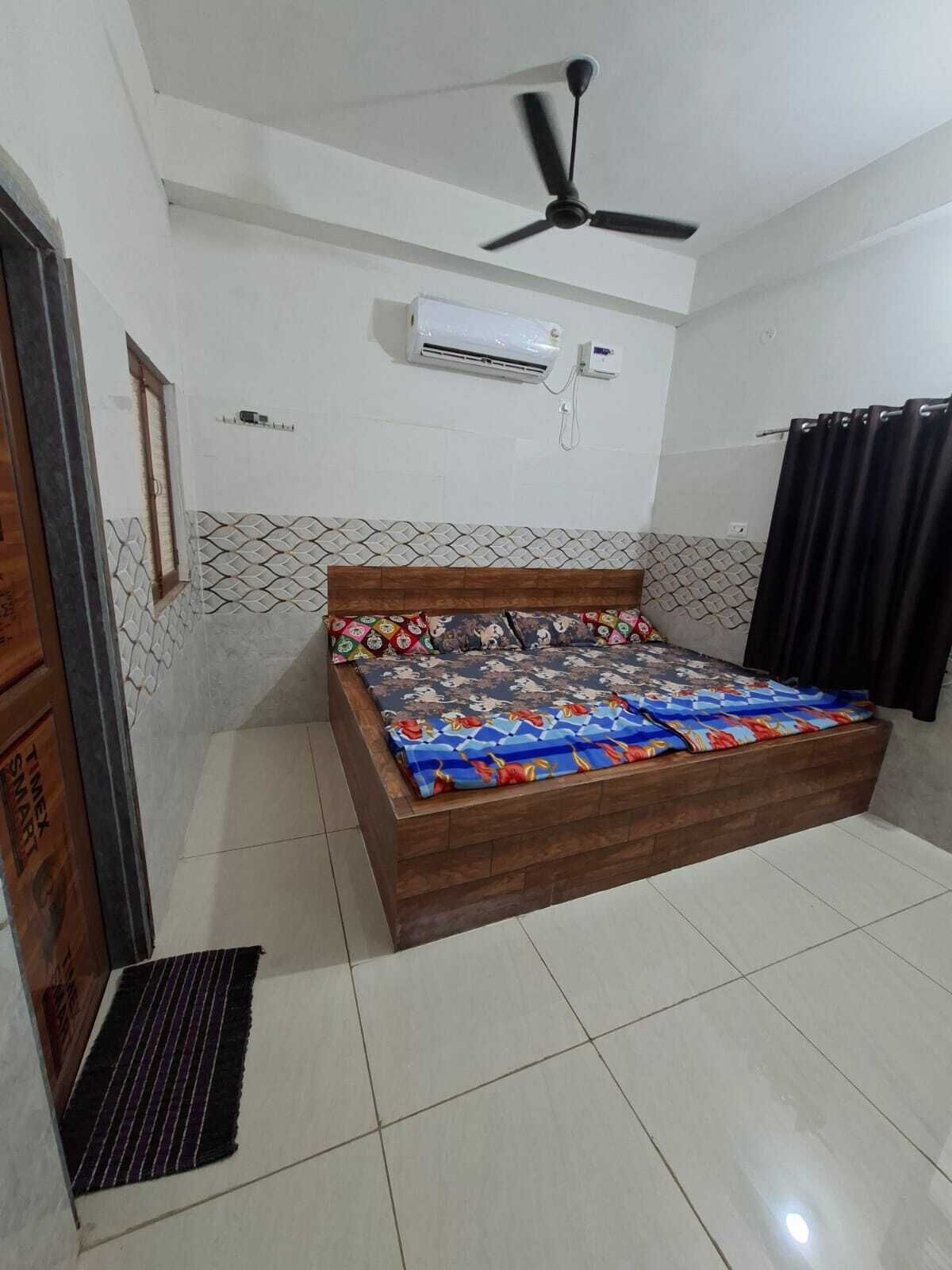 Um quarto com cama, ventoinha no teto, ar condicionado, janela e porta.