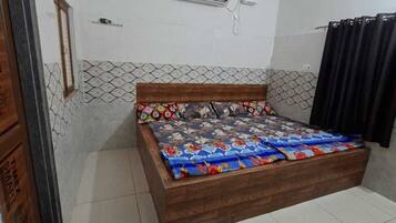 Um quarto com cama, ventoinha no teto, ar condicionado, janela e porta.