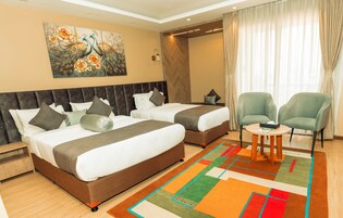 Quarto de hotel com duas camas, uma mesa pequena e uma cadeira.