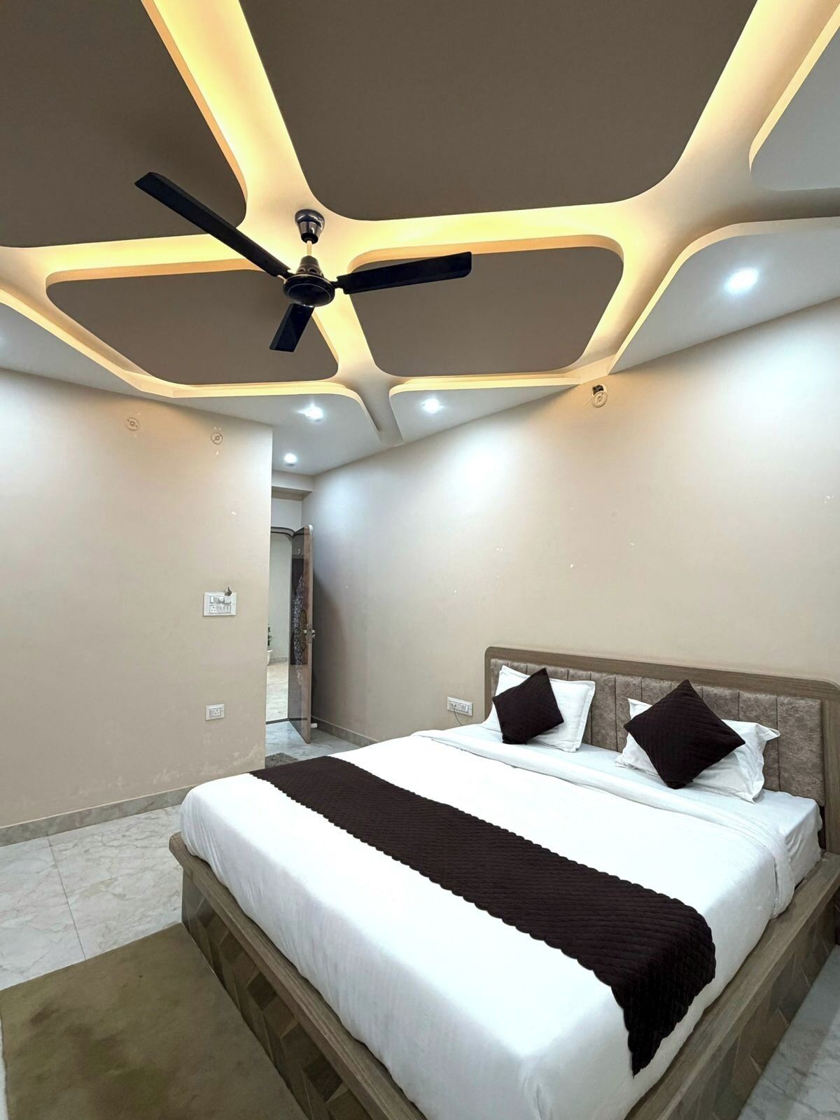 Quarto moderno com cama, ventoinha no teto, iluminação embutida e vista para o exterior.