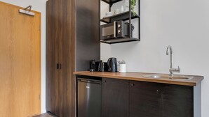 Uma cozinha moderna com bancada de madeira, máquina de lavar louça embutida, pia e prateleira para micro-ondas.