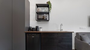 Uma cozinha compacta com micro-ondas integrado, cafeteira e pia.