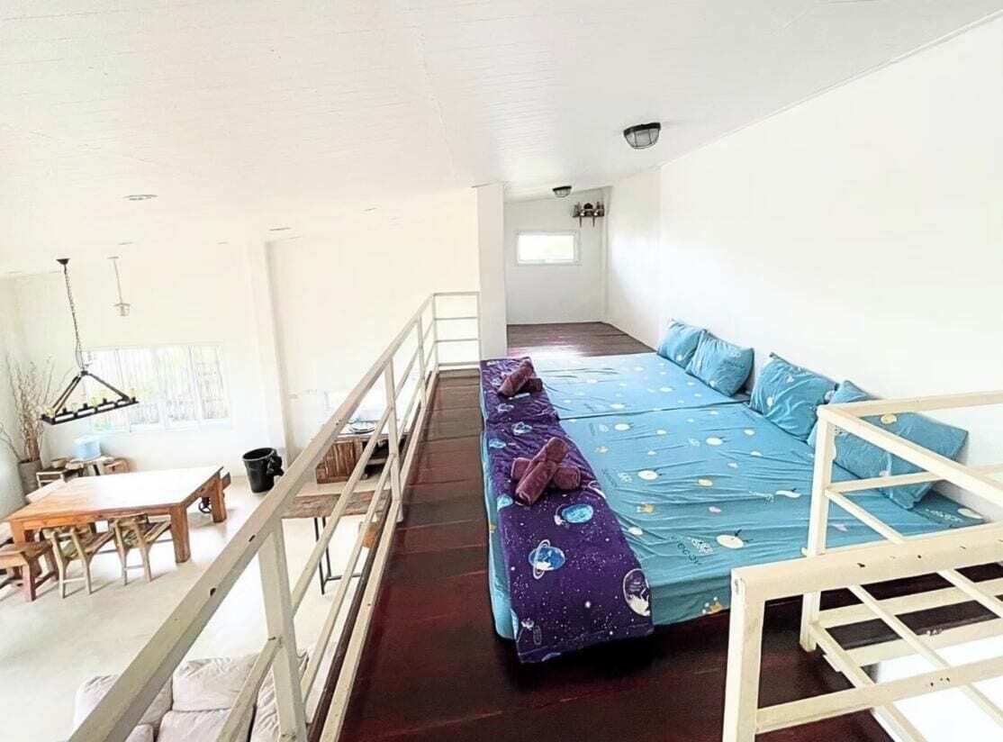 Quarto com uma cama de solteiro, uma escrivaninha e uma cadeira. Possui uma janela com cortinas e um lustre.
