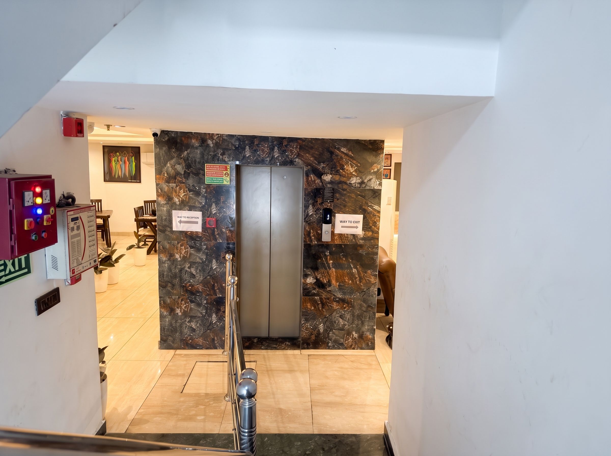 Um elevador com parede de mármore, placa de recepção e sinalização de saída.