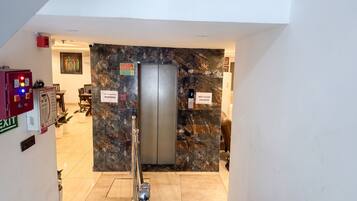 Um elevador com parede de mármore, placa de recepção e sinalização de saída.
