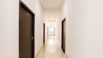 Um corredor com portas em ambos os lados, piso de azulejos e teto com iluminação embutida.