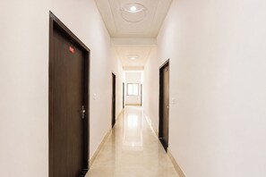 Um corredor com portas em ambos os lados, piso de azulejos e teto com iluminação embutida.