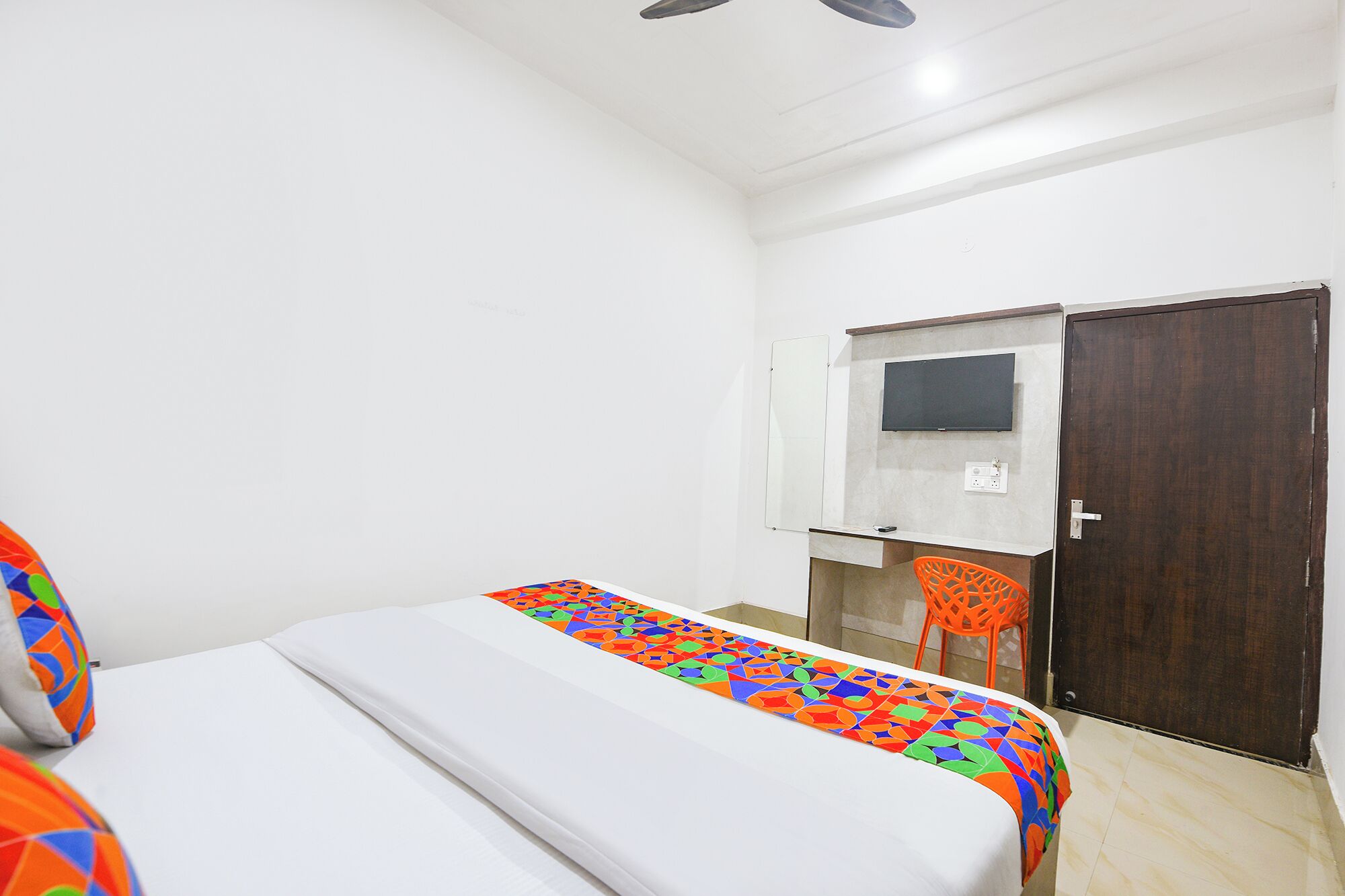 Um quarto com uma cama, uma escrivaninha com cadeira e uma porta.