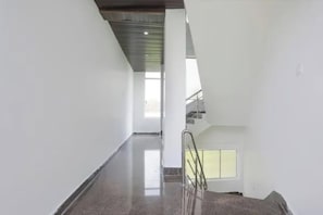 Um corredor com piso lustroso, paredes brancas e guarda-corpo de metal.