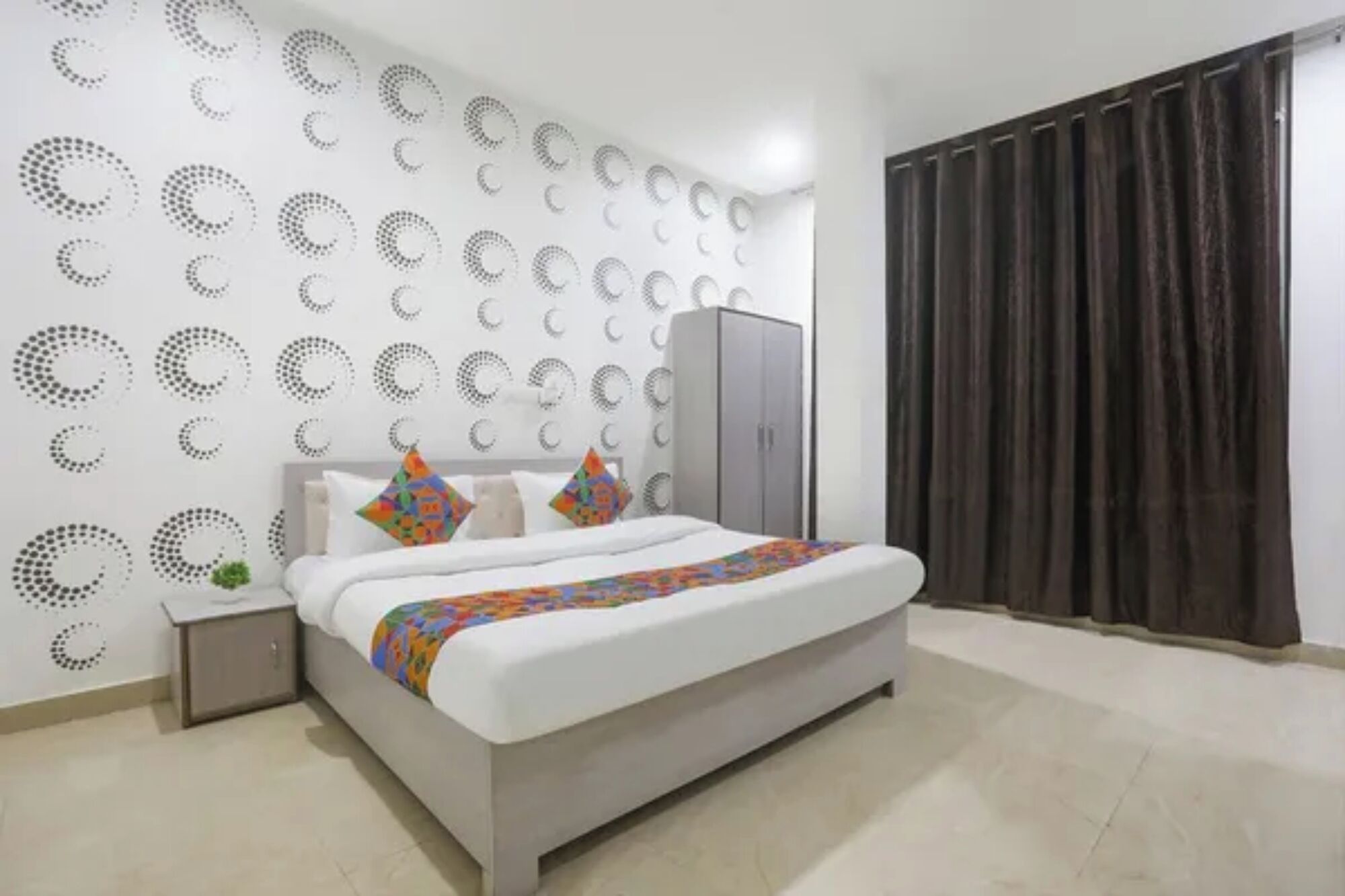 Quarto com cama, almofadas, guarda-roupa e cortina.