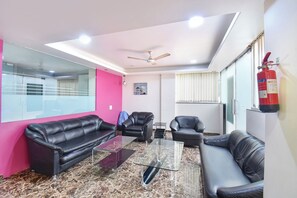 Uma sala de estar moderna com sofás de couro, uma mesa de centro de vidro e um ventilador de teto.