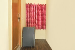 Um corredor com uma porta de madeira, uma cortina vermelha e um armário cinzento.