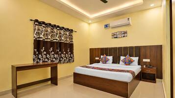 Quarto de hotel com cama, mesa de cabeceira, ar-condicionado e ventilador de teto.