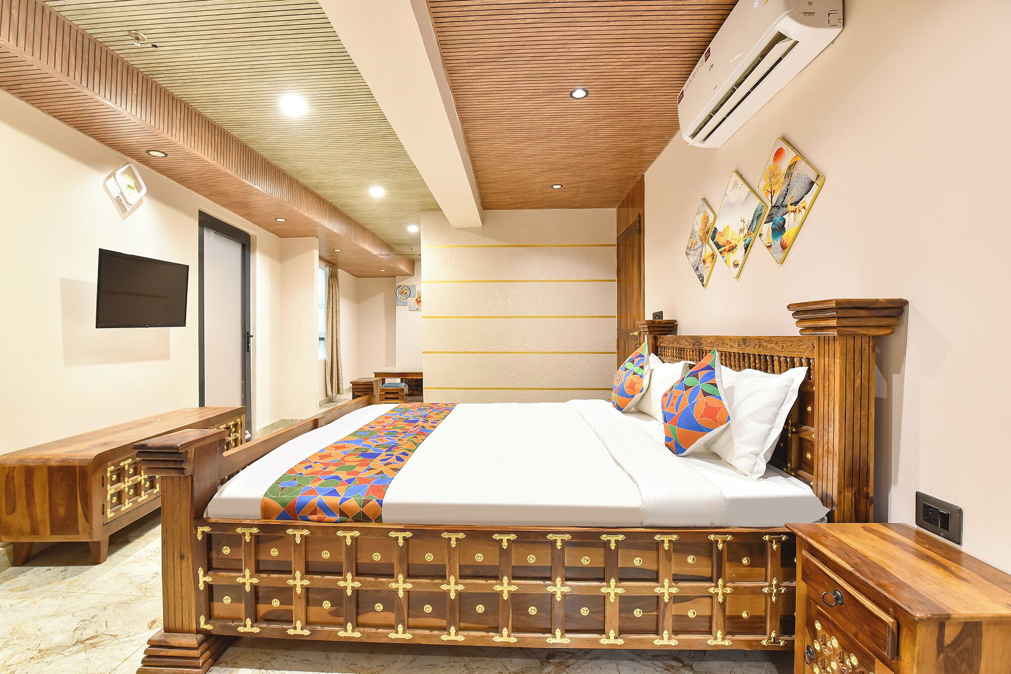 Quarto de hotel com cama de madeira, televisão de tela plana e teto com ripas de madeira.