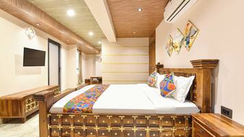 Quarto de hotel com cama de madeira, televisão de tela plana e teto com ripas de madeira.