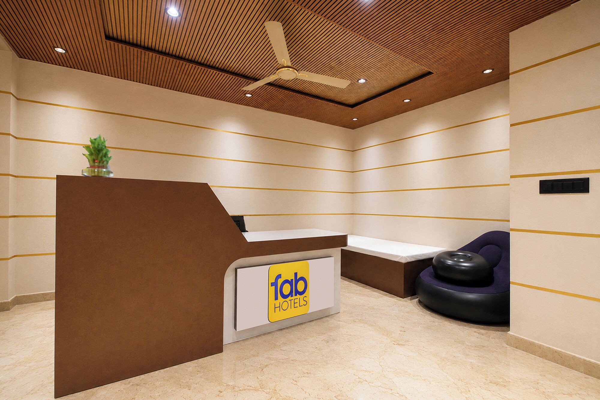 Uma área de recepção de hotel com design moderno, incluindo balcão de atendimento, espaço de estar e um ventilador de teto.