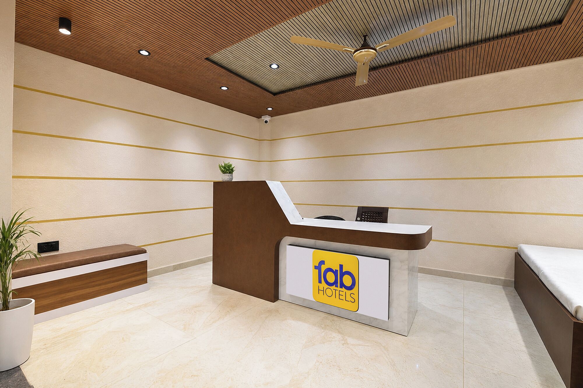 Uma mesa de recepção com um logotipo, um ventilador de teto e uma planta.