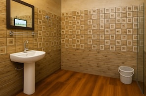 Um banheiro com piso de madeira, pia branca, espelho e parede revestida com azulejos.