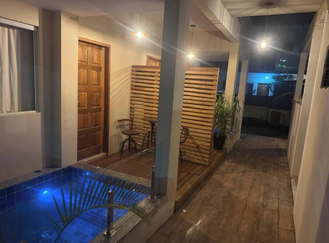 Uma área de piscina com um deck de madeira, uma porta e um espaço de estar com cadeiras.