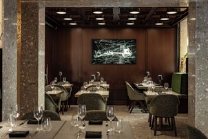 Um restaurante com mesas montadas para refeições, uma grande obra de arte na parede e um design de teto moderno.