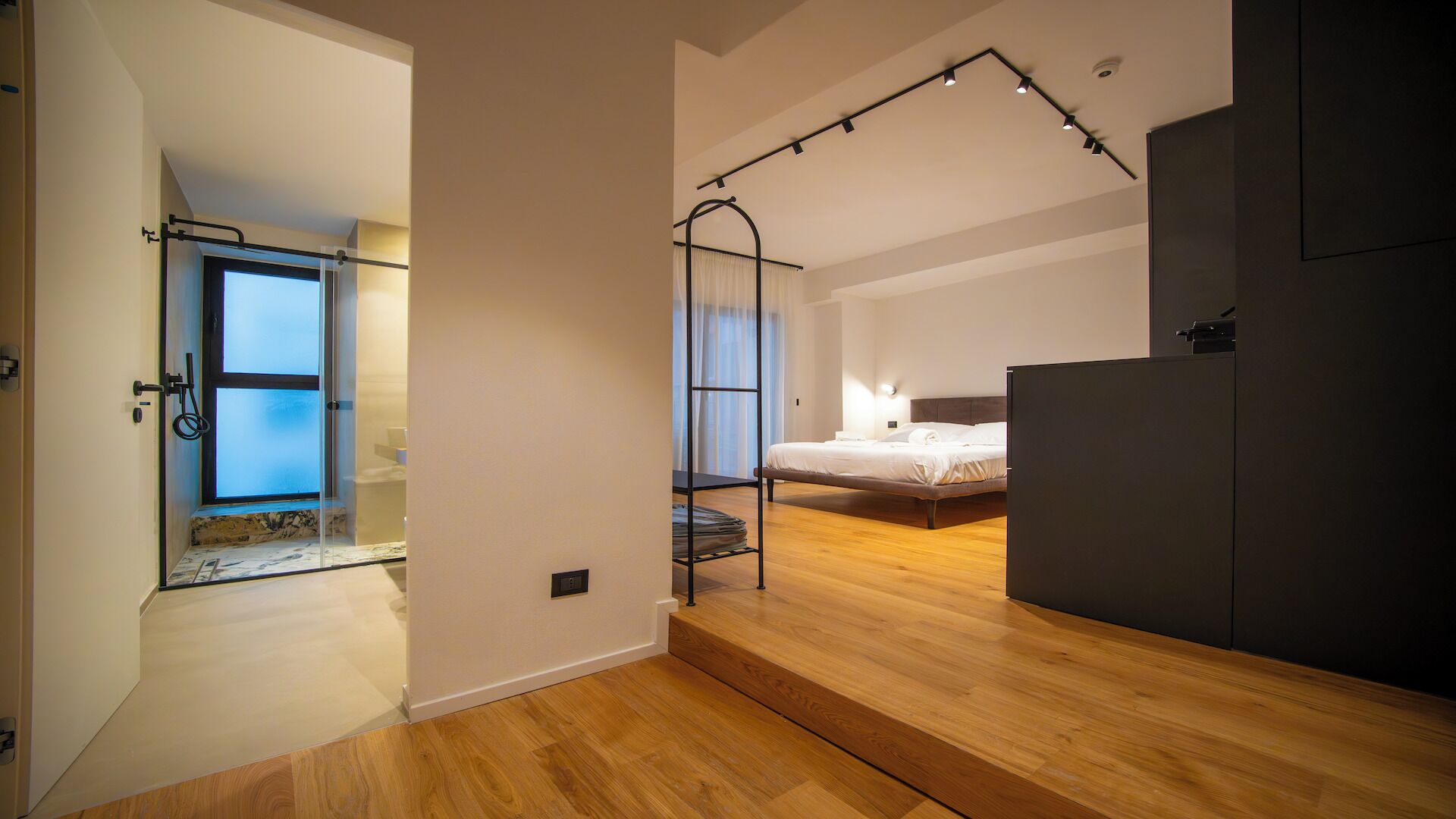 Quarto moderno com piso de madeira, uma cama, escrivaninha e guarda-roupa.