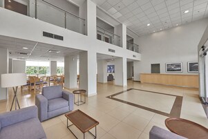 Um hall amplo com teto alto, balcão de recepção e áreas de estar.
