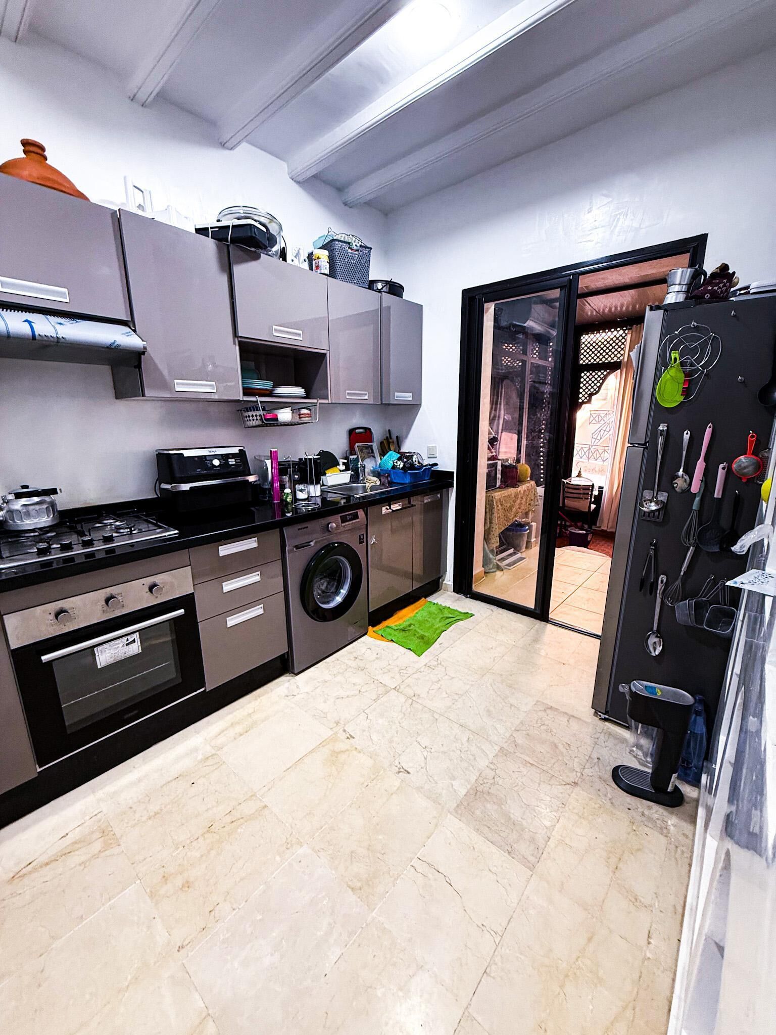 Uma cozinha compacta com fogão a gás, forno, máquina de lavar e frigorífico.