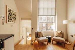 Uma sala de estar moderna com uma janela grande, um sofá, uma mesa de centro e um quadro na parede.